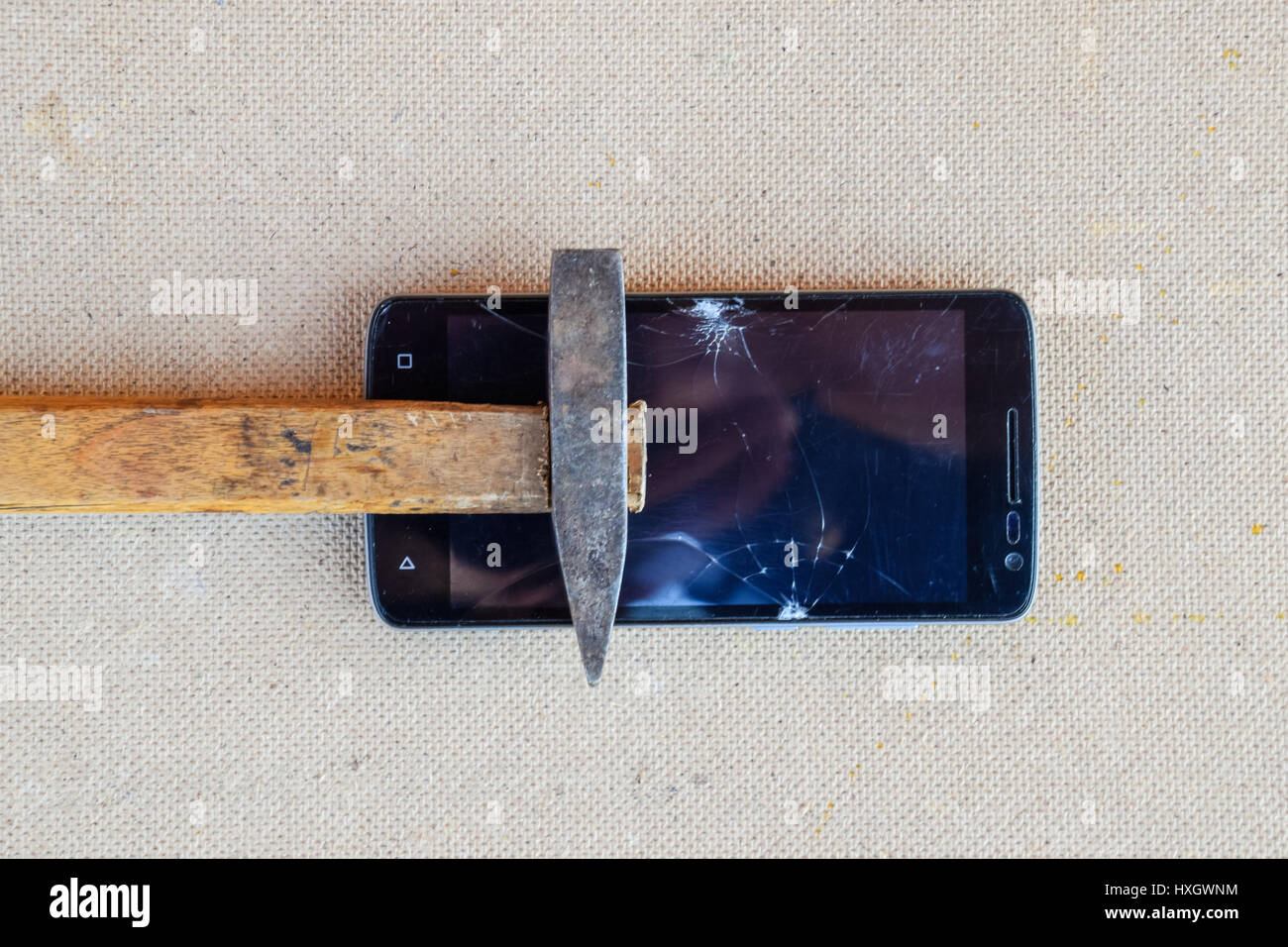 Hammer and smartphone. The screen of the smartphone, a broken hammer ...