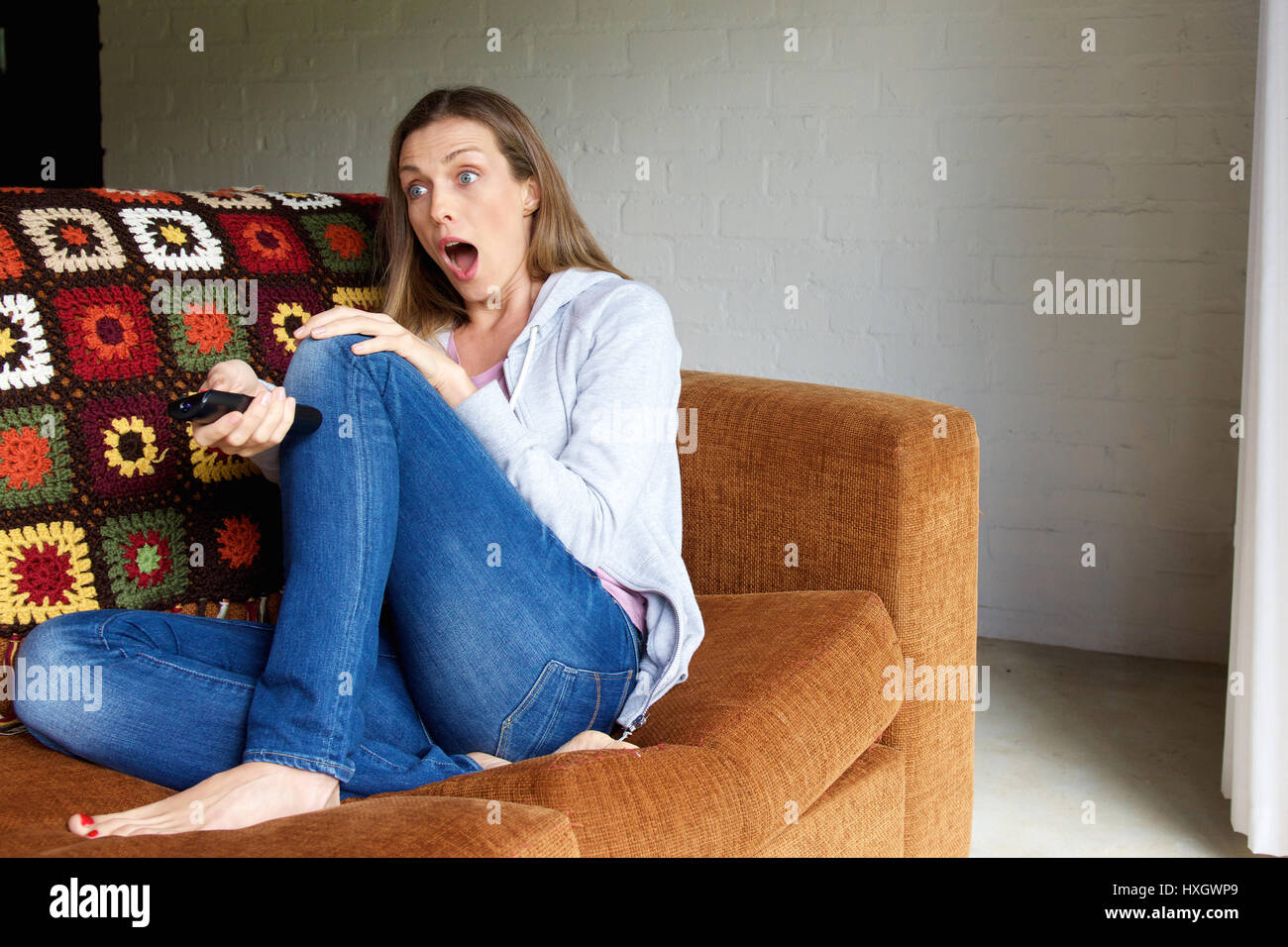 Portrait of a woman with surprised face expression watching tv Stock ...