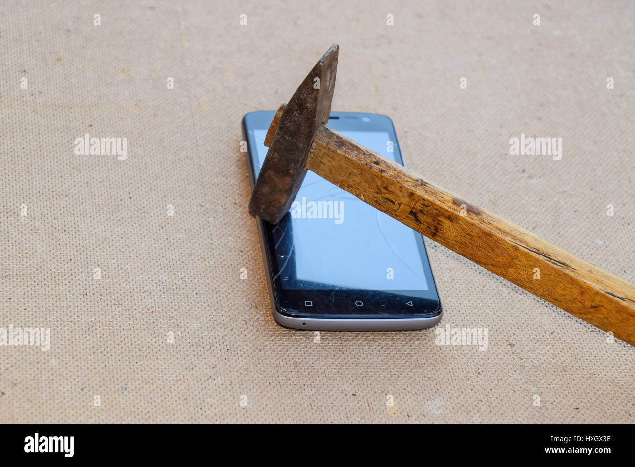 Hammer and smartphone. The screen of the smartphone, a broken hammer ...