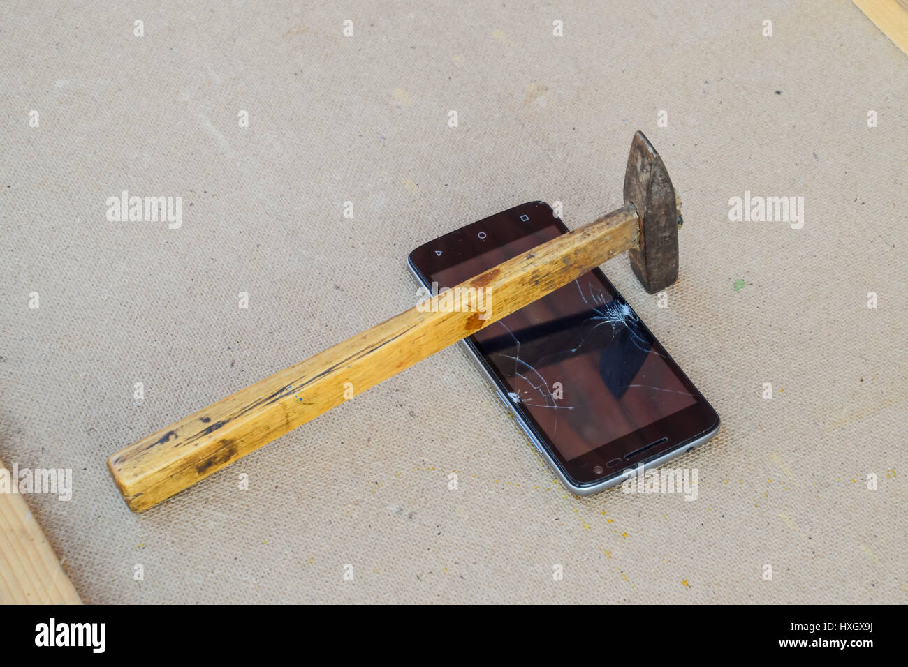 Hammer and smartphone. The screen of the smartphone, a broken hammer ...