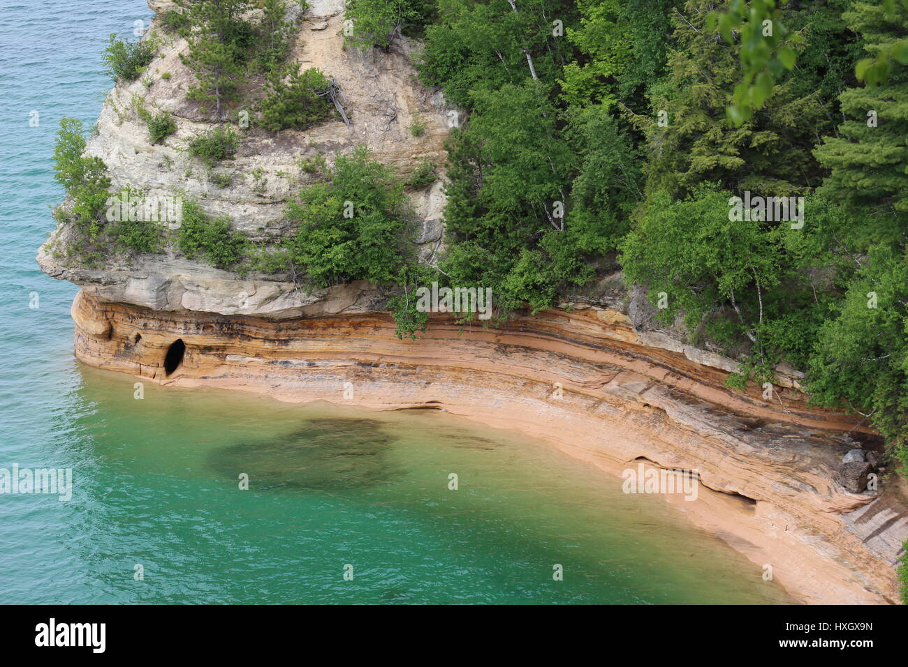 Breathtaking cliff view with crystal clear blue water and green trees ...