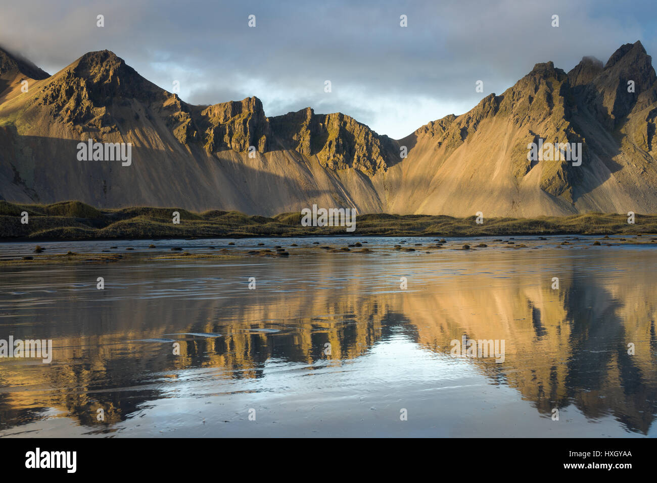 Stokksnes and Vestrahorn mountains with clouds above them reflected in ...