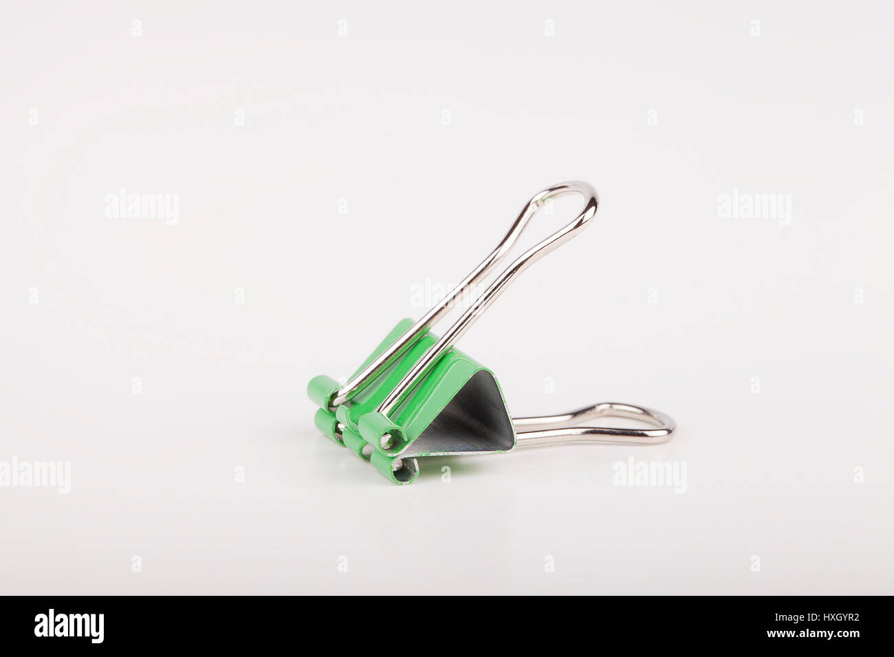 Green paper clip on a white surface. Paperclip isolated on white ...