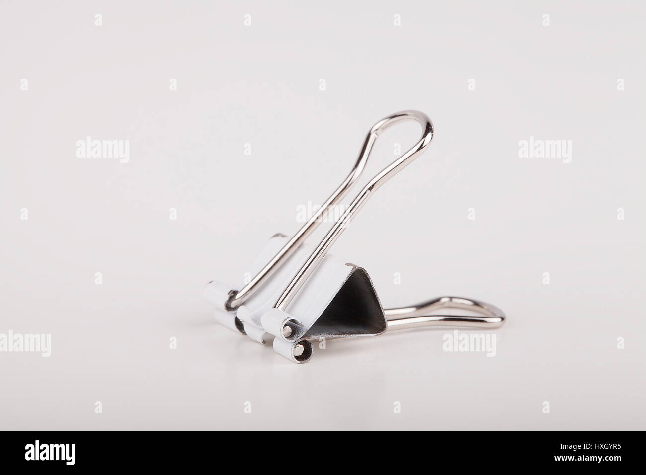 White paper clip on a white surface. Paperclip isolated on white ...