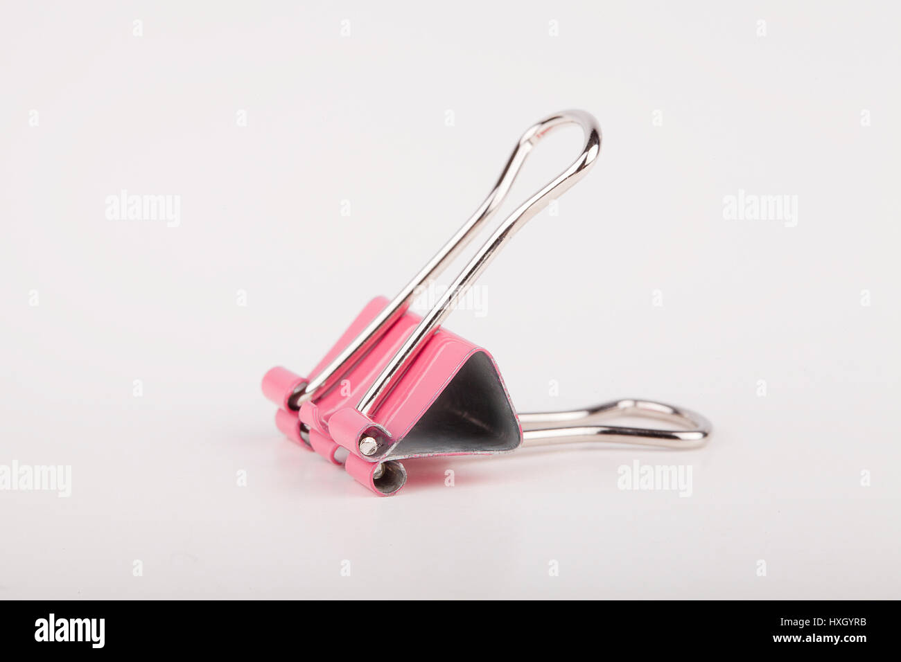 Pink paper clip on a white surface. Paperclip isolated on white ...