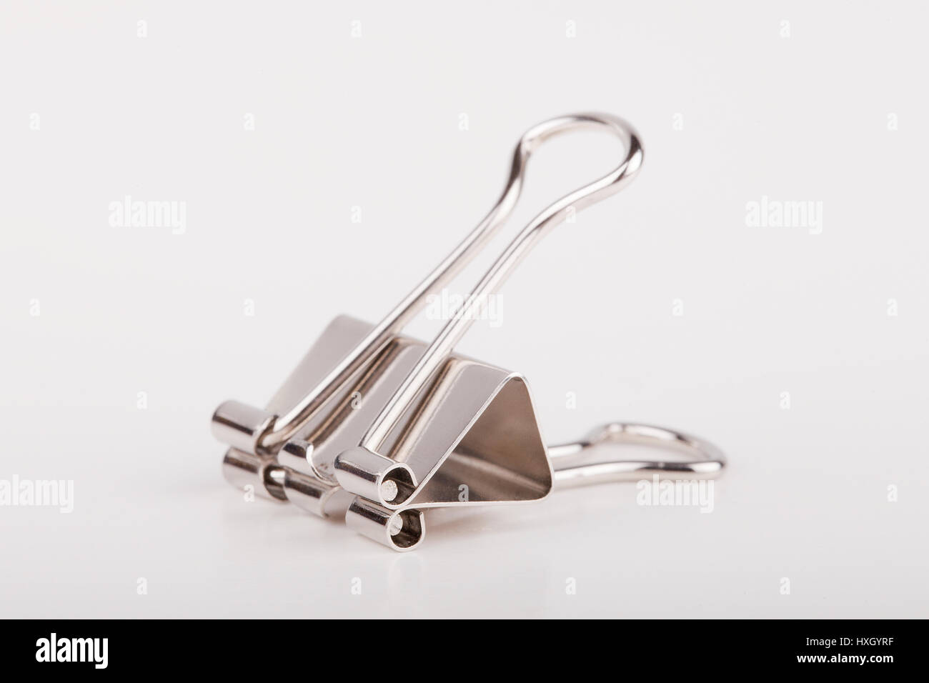 Silver paper clip on a white surface. Paperclip isolated on white ...