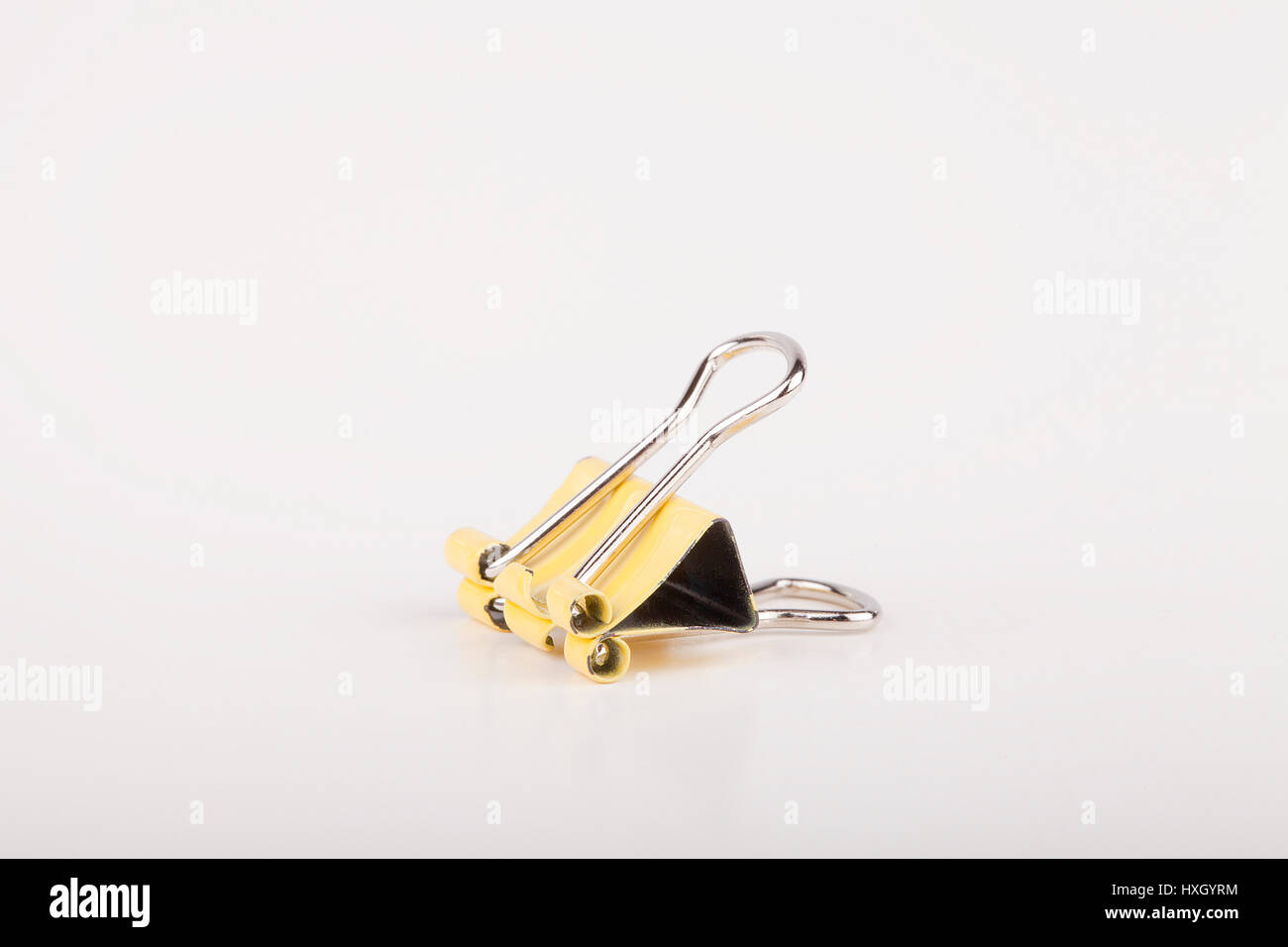 Yellow paper clip on a white surface. Paperclip isolated on white ...