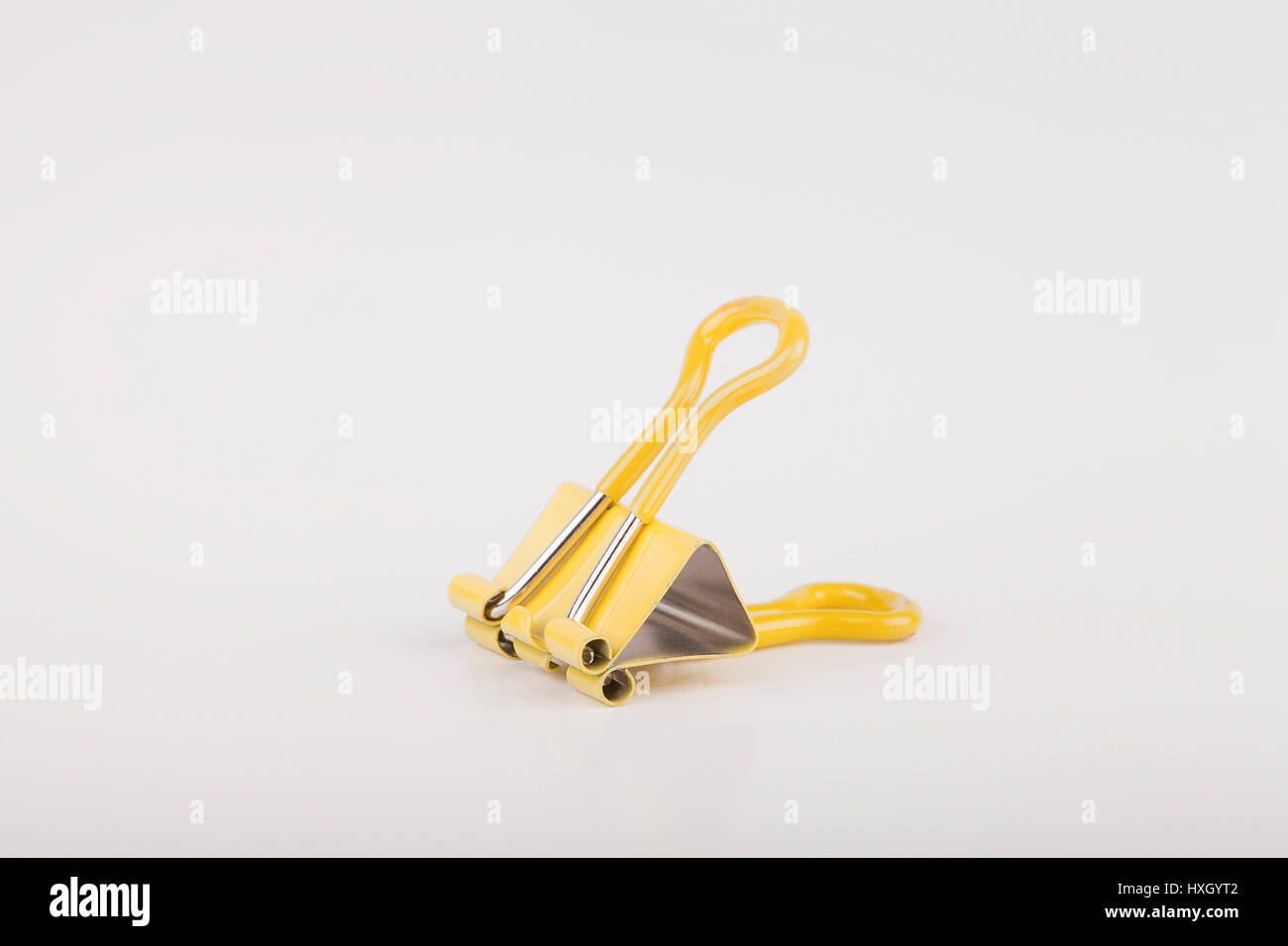 Yellow paper clip on a white surface. Paperclip isolated on white ...