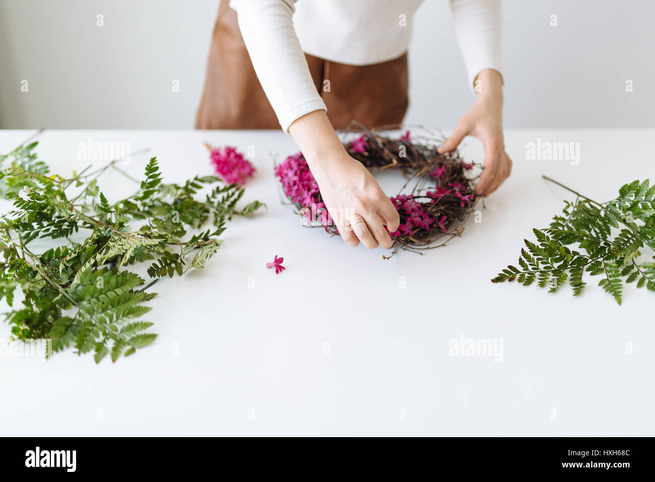Girl florist makes a bouquet in the form of a nest on a white table ...