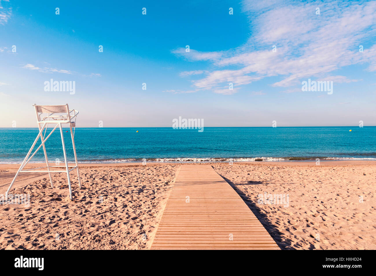 empty sand beach with wooden pathway and white rescue watch seat in ...
