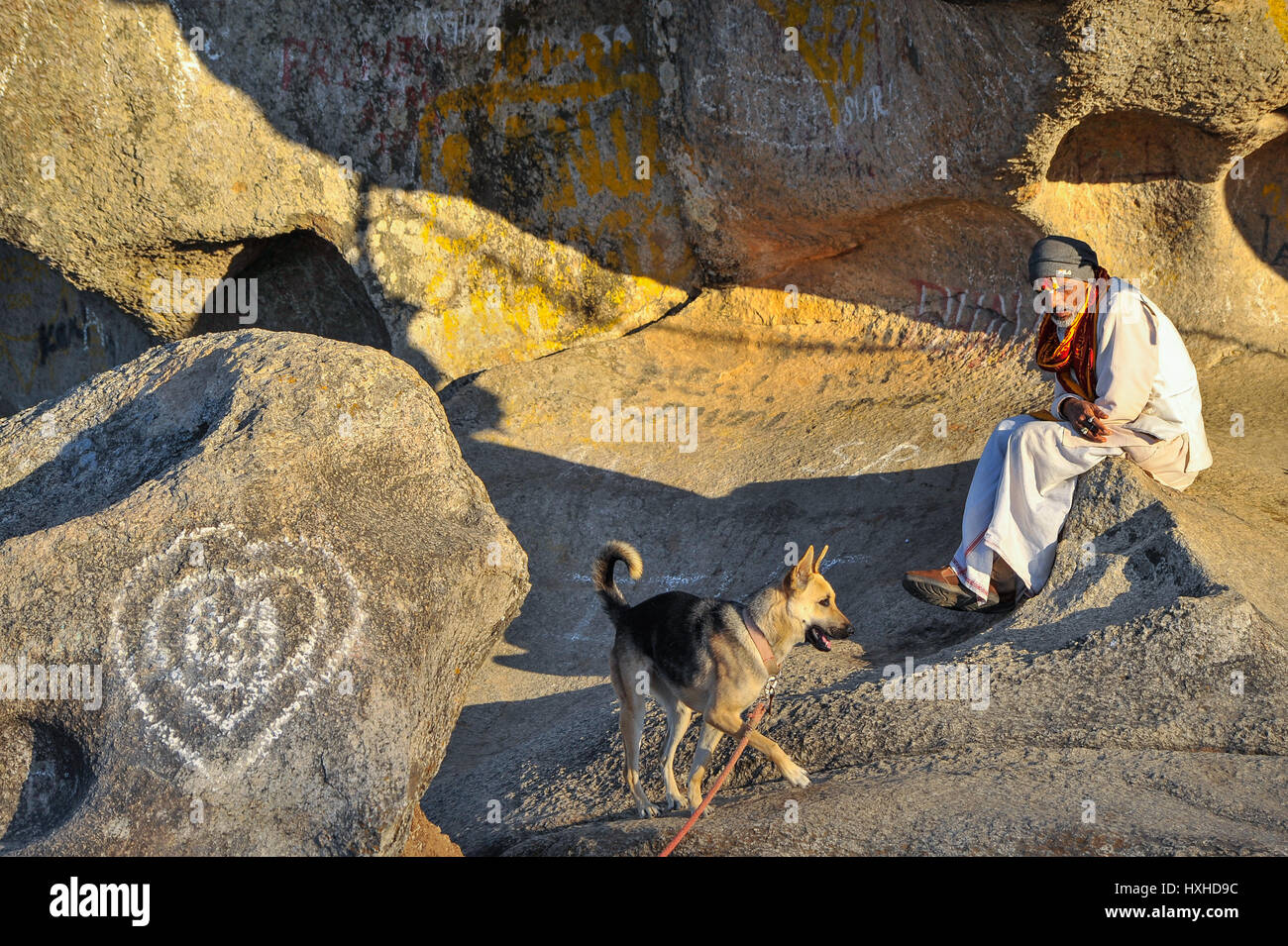 Man with his Alsatian dog sitting amongst chalk daubed stones at Toad ...