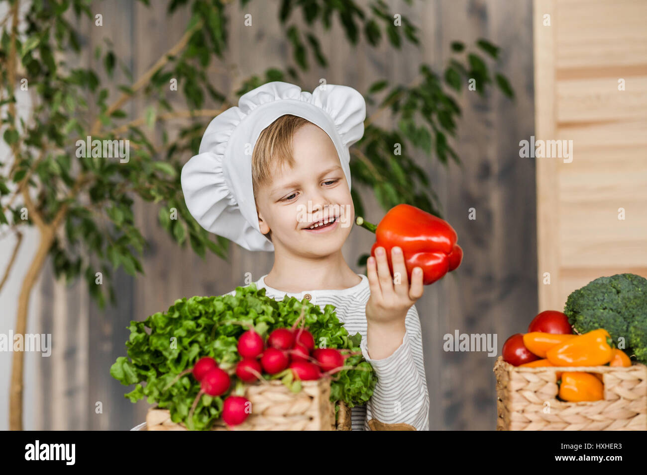 Handsome little kid in chef uniform with vegetables. Cooking in kitchen ...