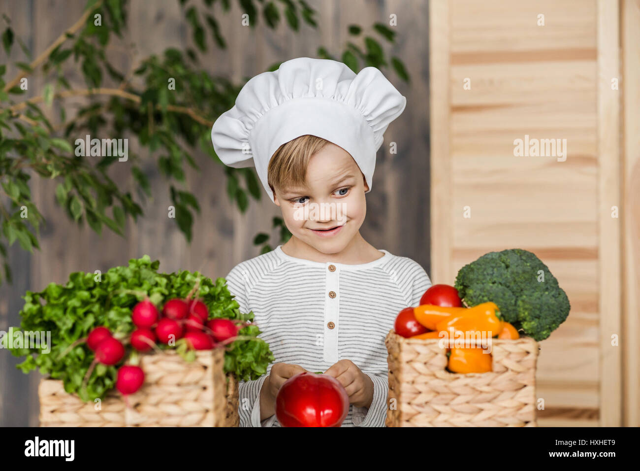 Handsome little kid in chef uniform with vegetables. Cooking in kitchen ...