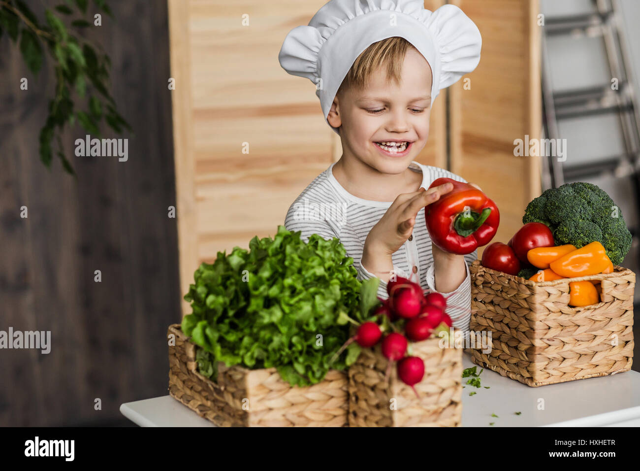 Handsome little kid in chef uniform with vegetables. Cooking in kitchen ...