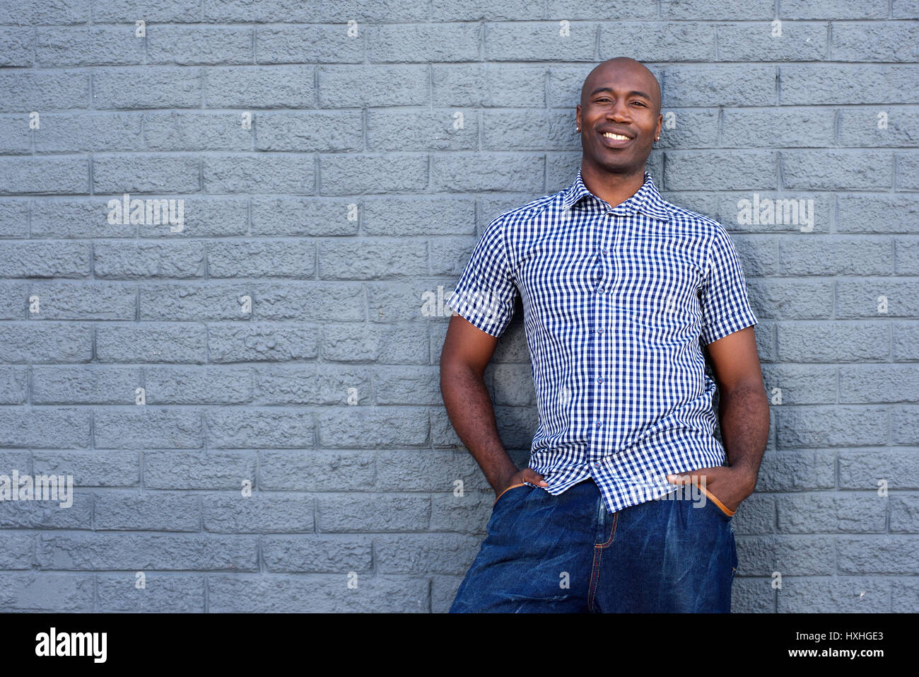 Portrait of handsome african american man standing against a gray wall ...