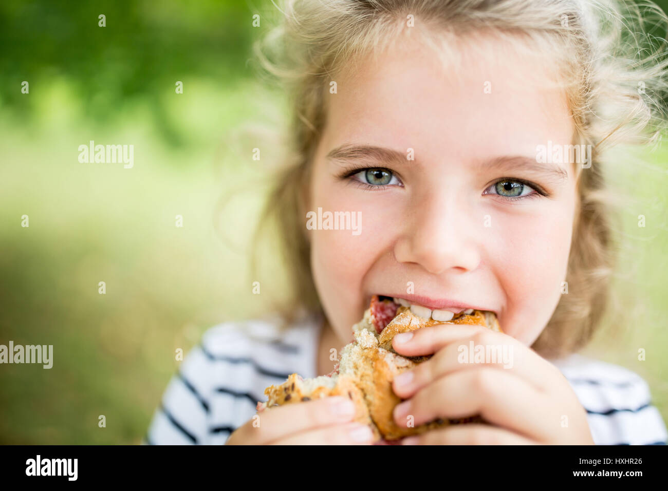 Blond child eats bun as a snack in summer Stock Photo - Alamy