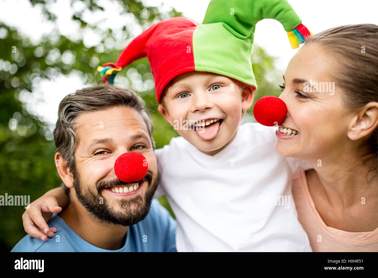 Happy boy wearing fool cap with parents in carnival Stock Photo - Alamy