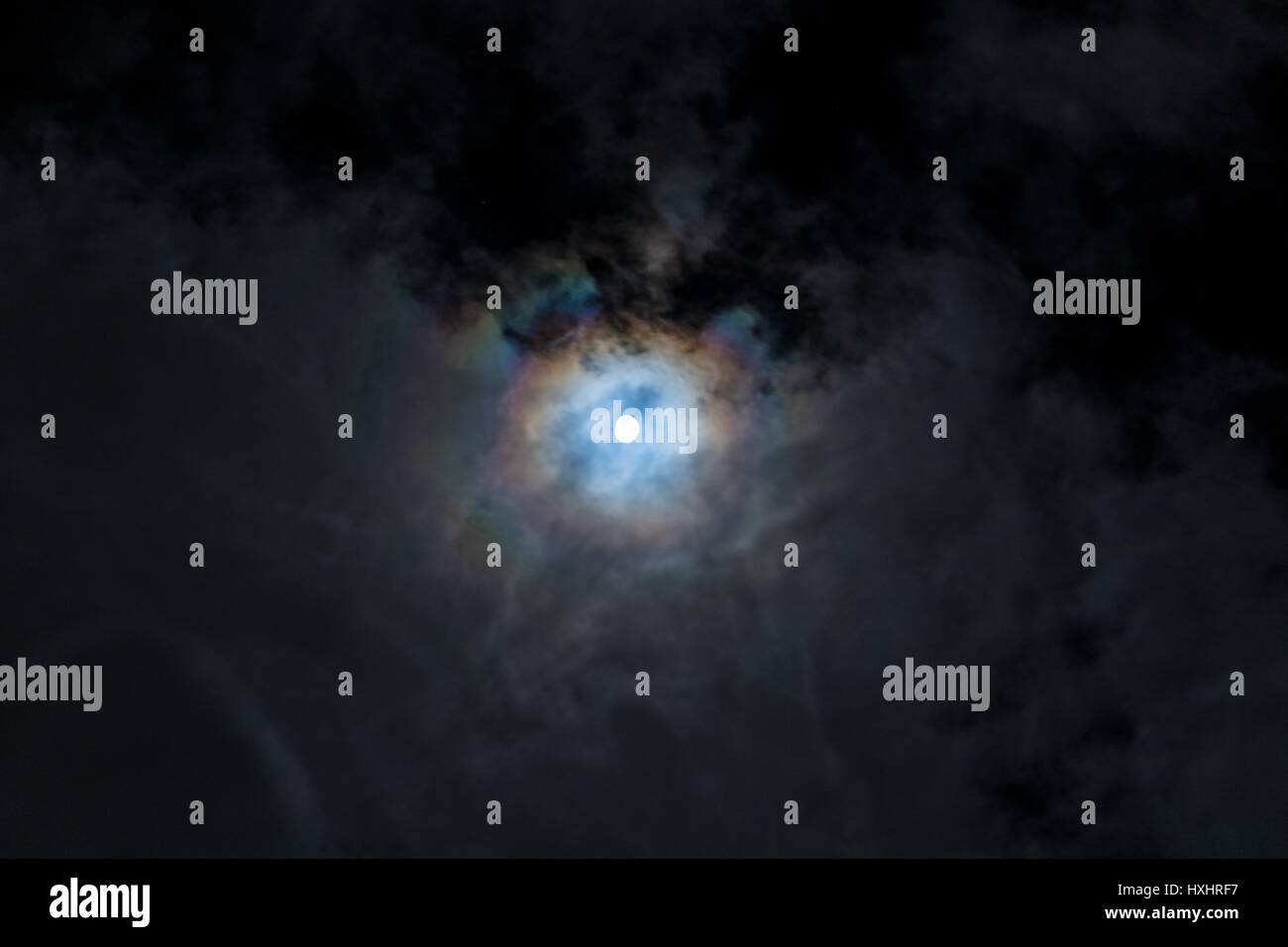 Long exposure of the moon with rolling clouds, and refracted rings of ...