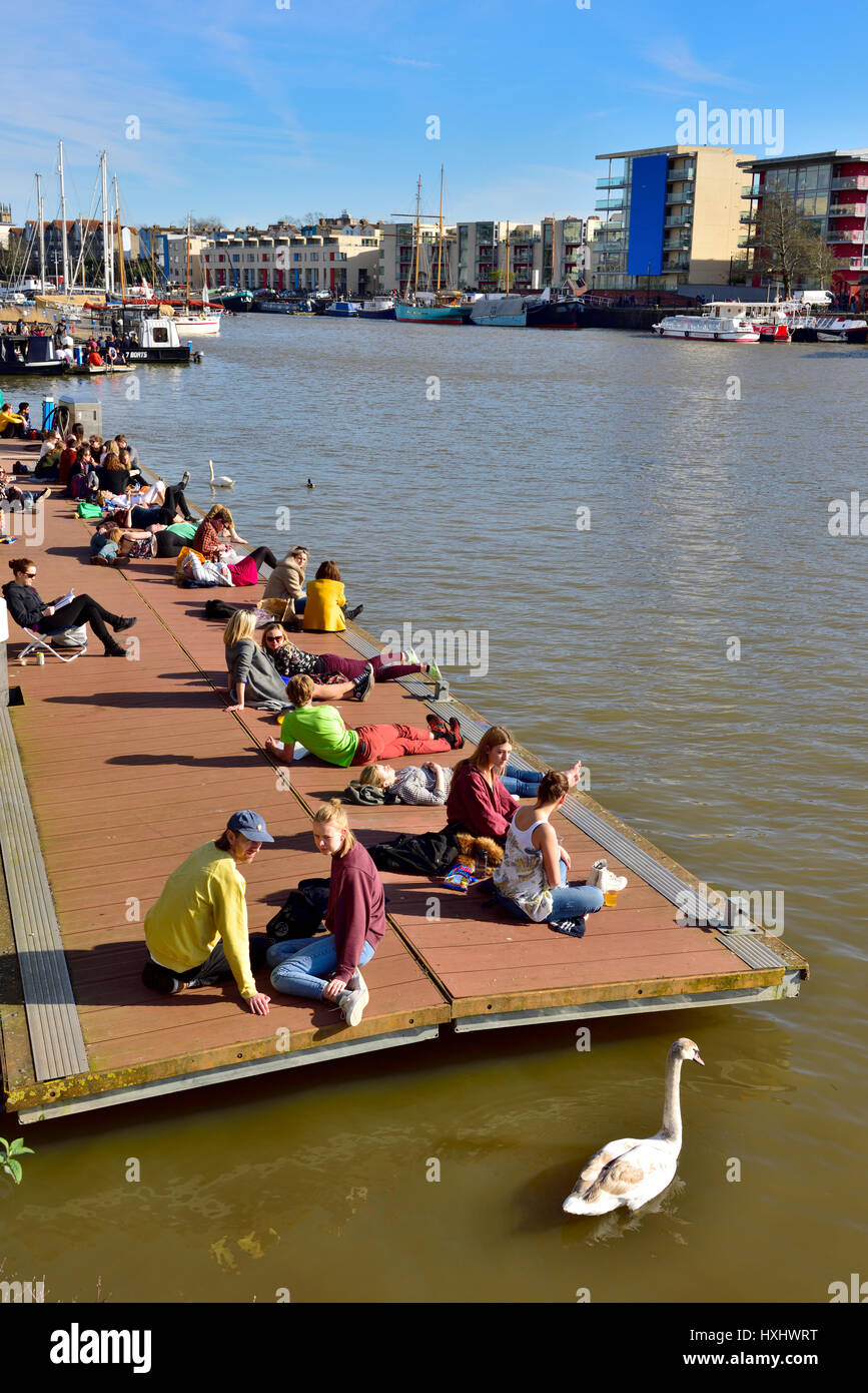 Warm sunny day with people sitting out on floating dock in Bristol city ...