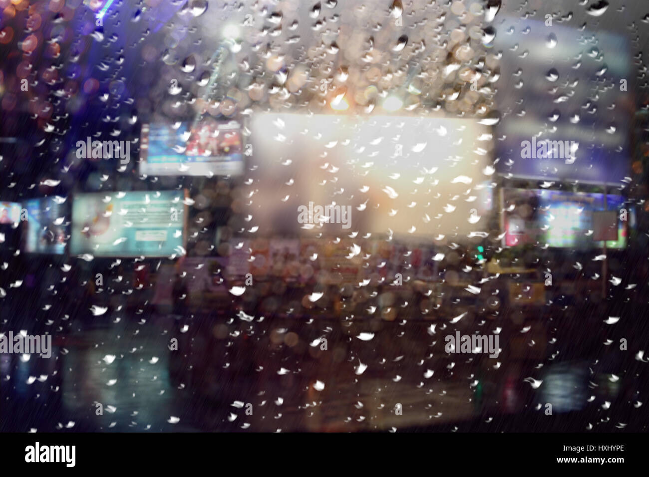 City life in night in rainy season. Looking through the window glass ...
