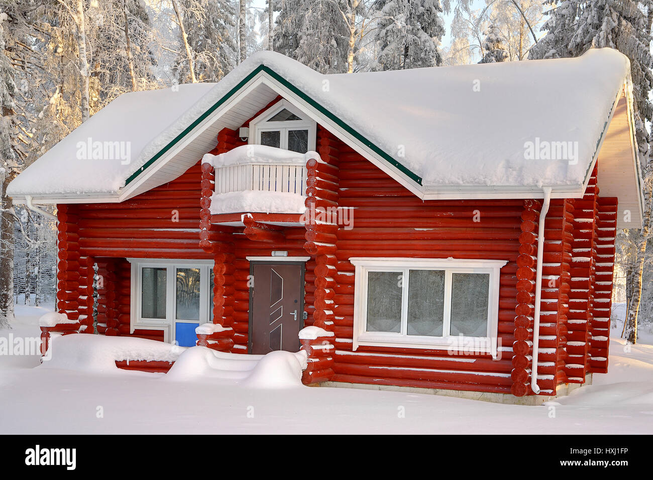 Wooden cottage of red painted logs, with snow-covered roof on ...