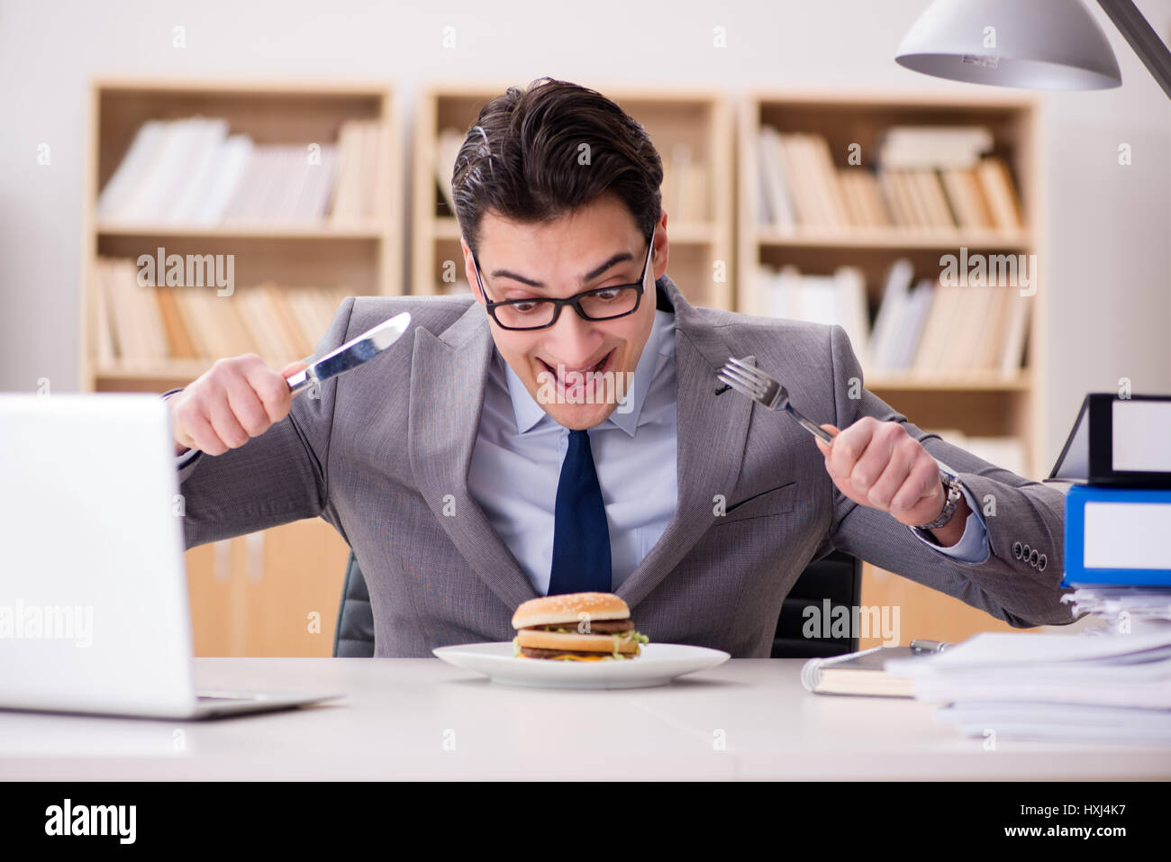 Hungry funny businessman eating junk food sandwich Stock Photo - Alamy