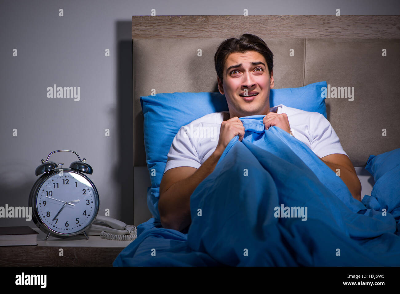 Young man scared in bed Stock Photo - Alamy