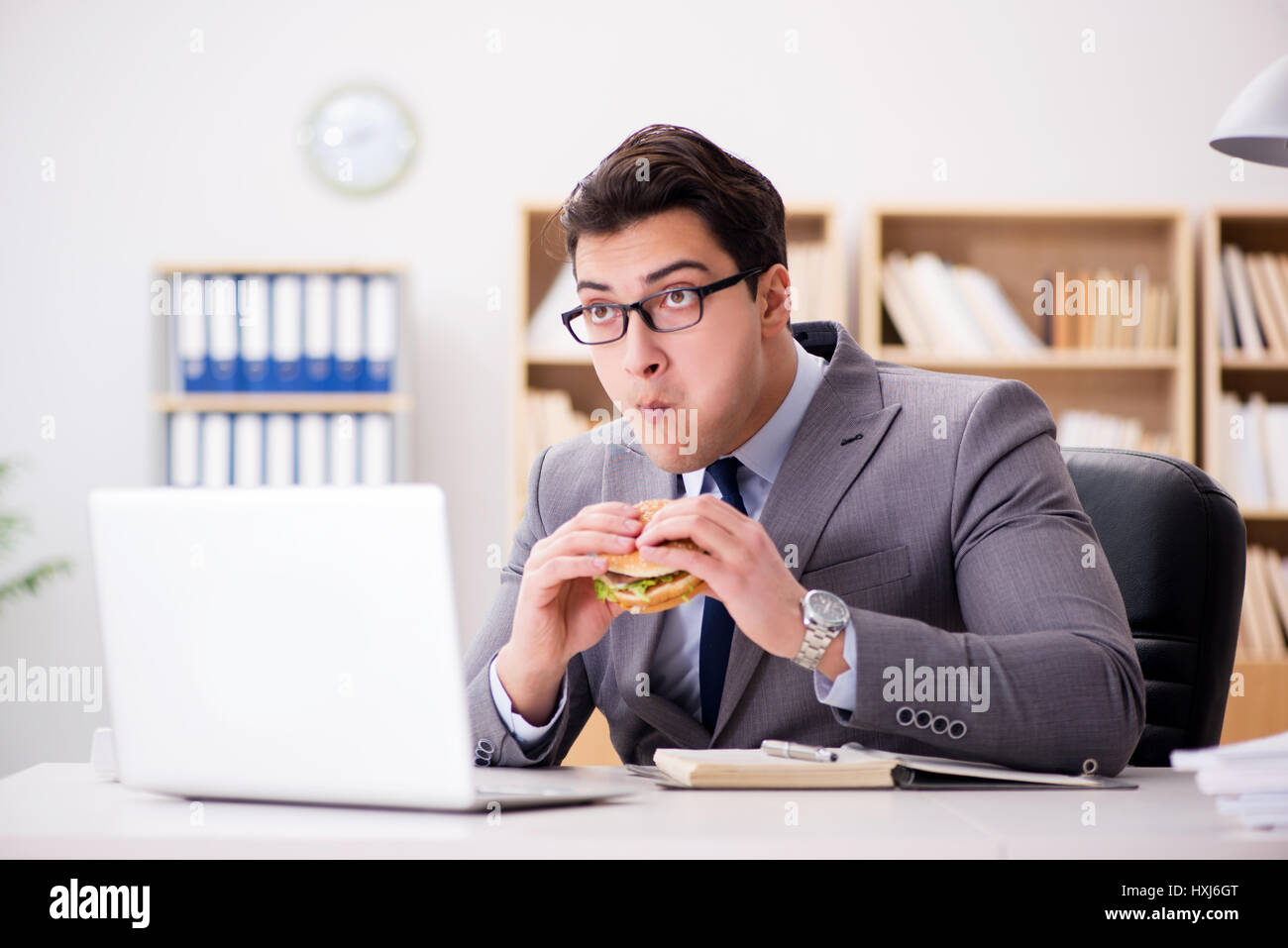 Hungry funny businessman eating junk food sandwich Stock Photo - Alamy