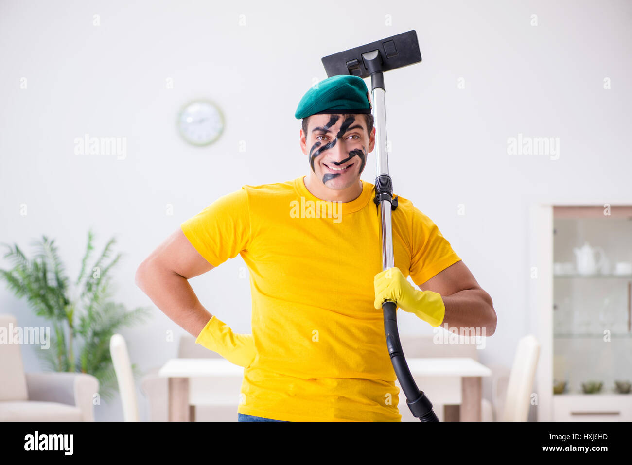 Funny man in military style cleaning the house Stock Photo - Alamy