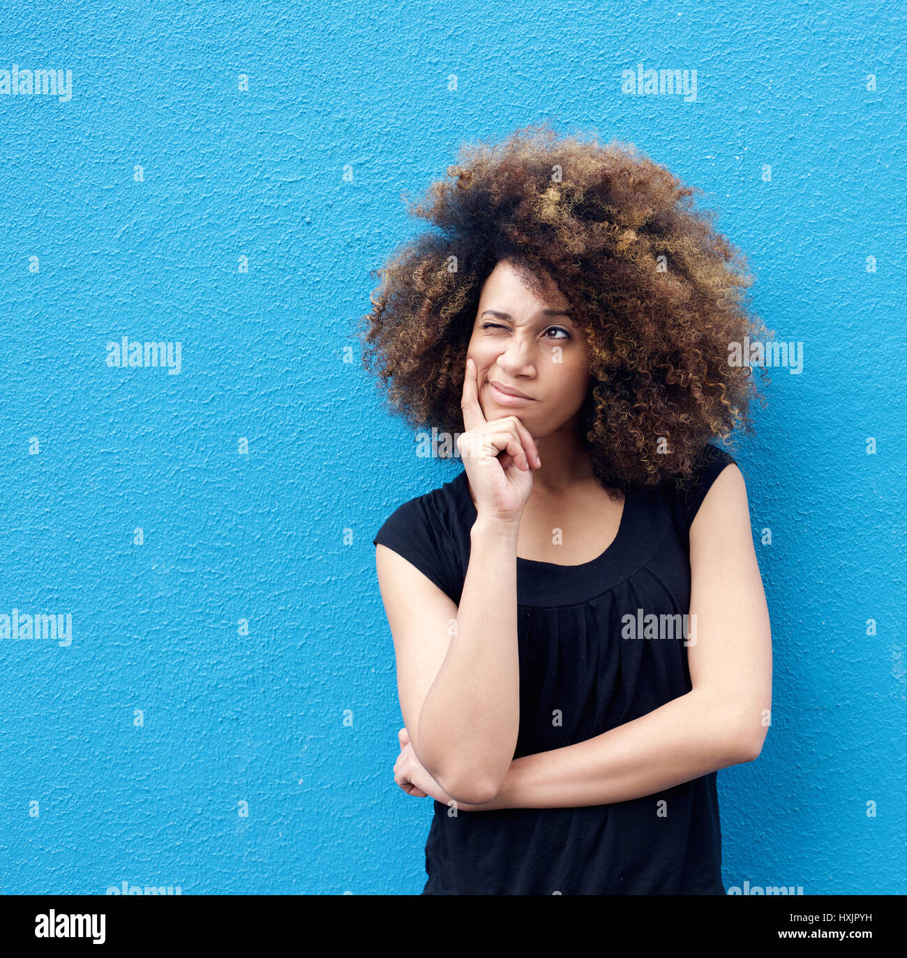 Portrait of young afro woman thinking against blue background Stock ...