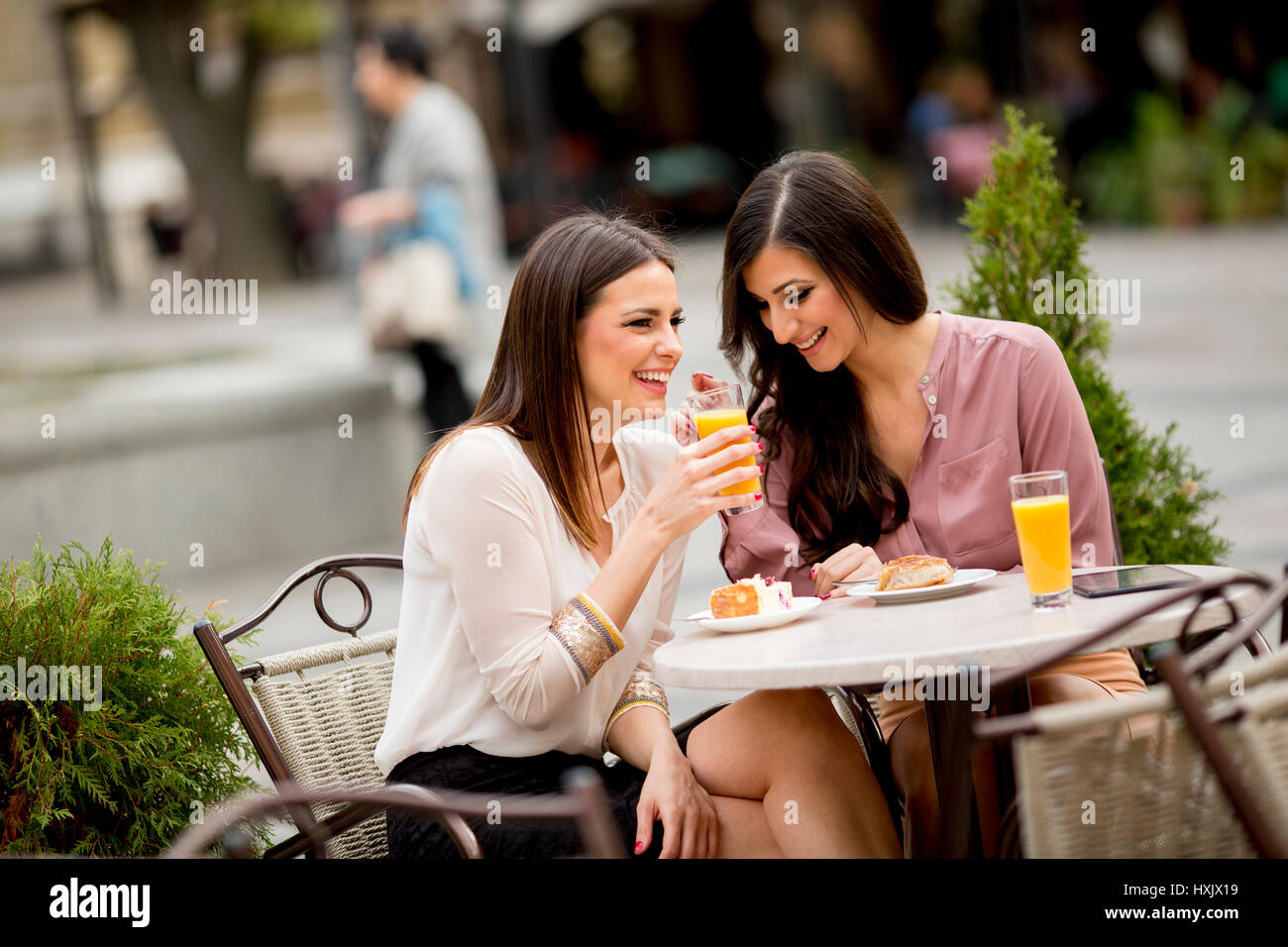 Two female friends sitting outside in a cafe and have fun Stock Photo ...