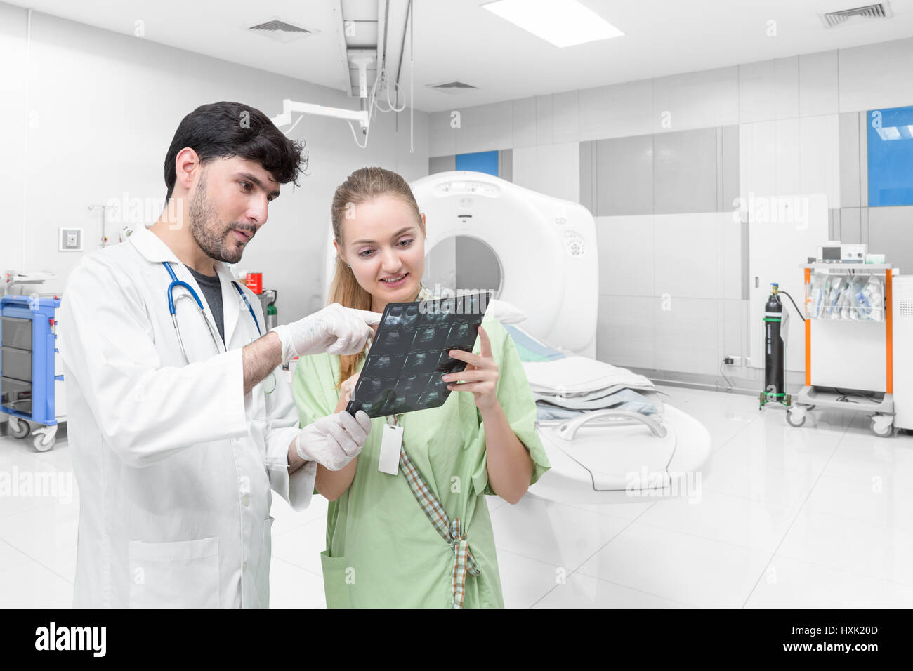 Doctor in CT scan room examining an x-ray and discussing with a patient ...