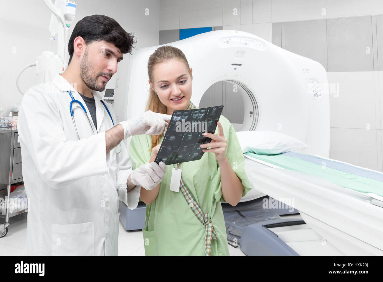 Doctor in CT scan room examining an x-ray and discussing with a patient ...