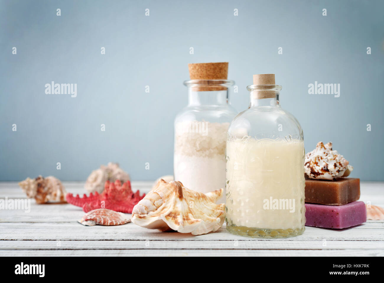 Bottles with shampoo and sea salt with sea shells on light background ...