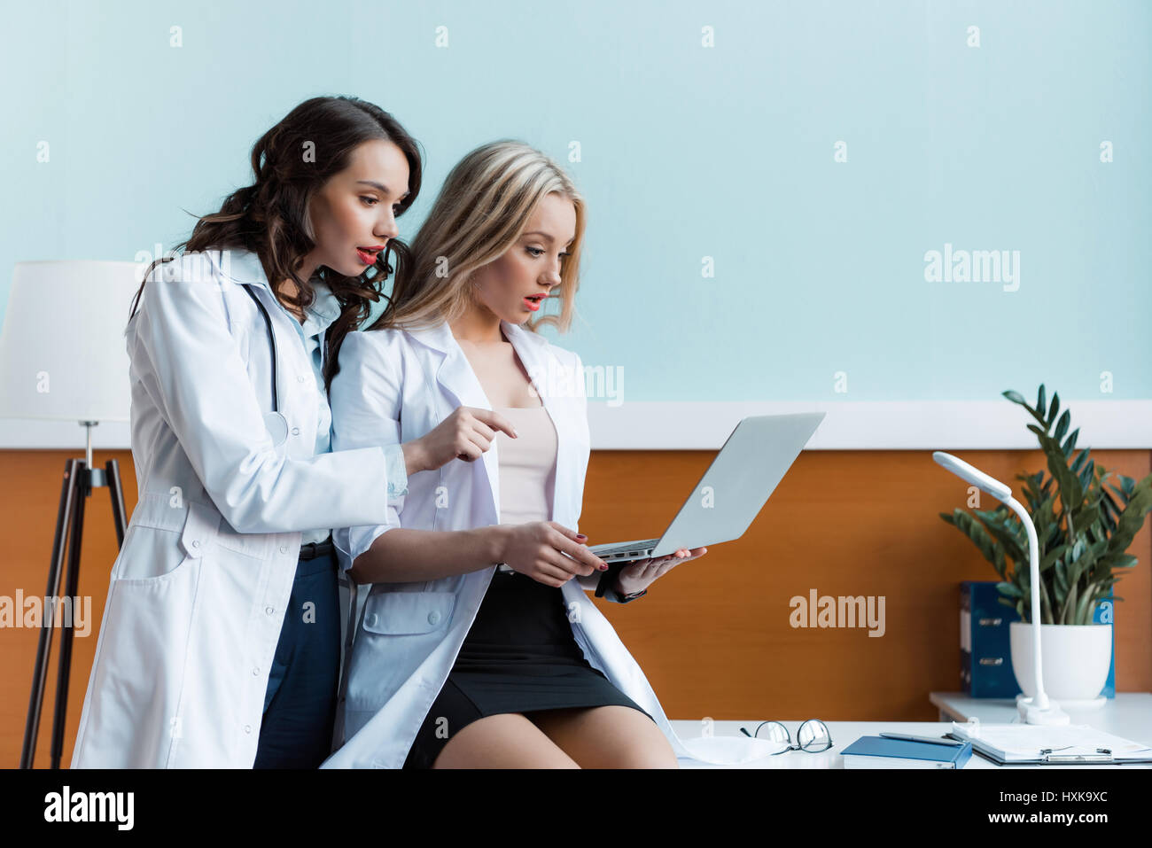 side view of shocked professional doctors in medical uniforms using ...