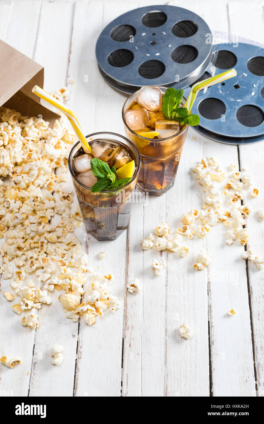 Close-up view of popcorn with iced tea in glasses and film reels on ...