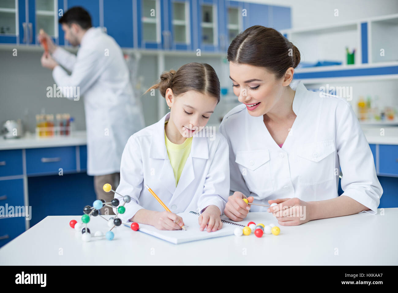 Smiling teacher and student scientists working with molecular model and ...