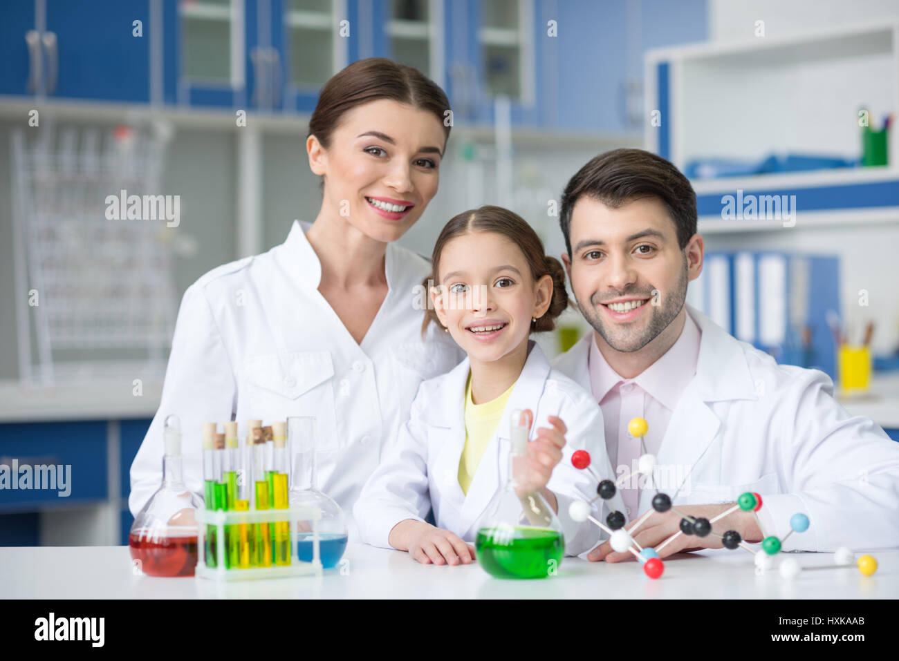 Happy adult scientists and little girl student working together in ...