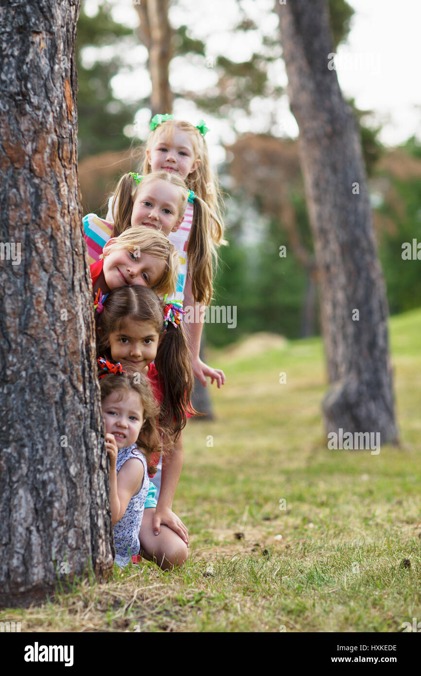 Friends hiding behind tree Stock Photo - Alamy