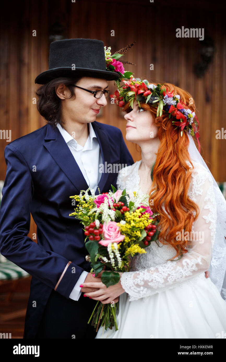 Close-up of boho young wedding couple, red hair bride with flowers ...