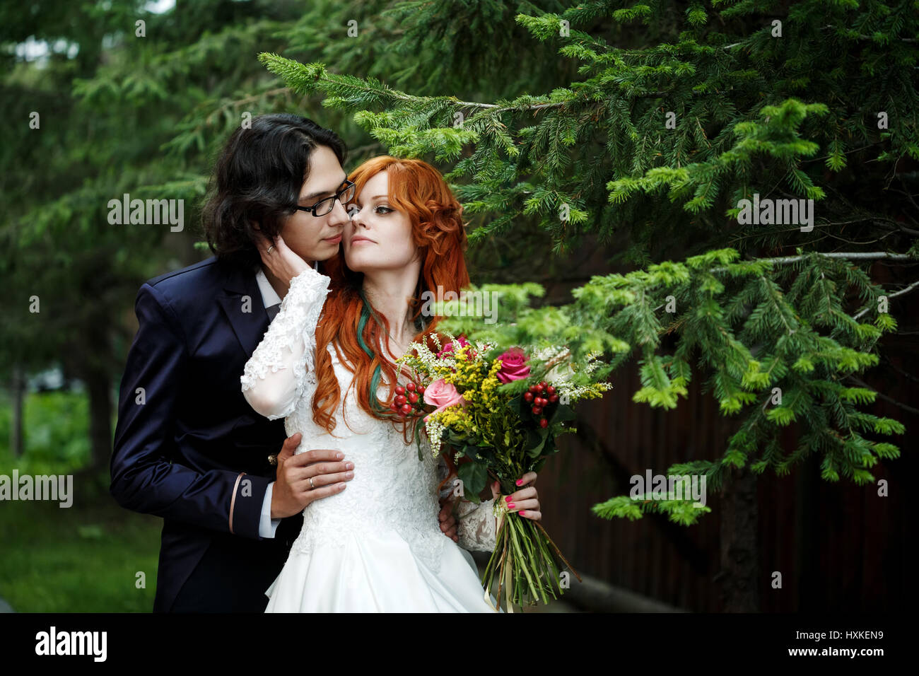 Close-up of happy boho wedding couple, red hair bride. Couple kissing ...