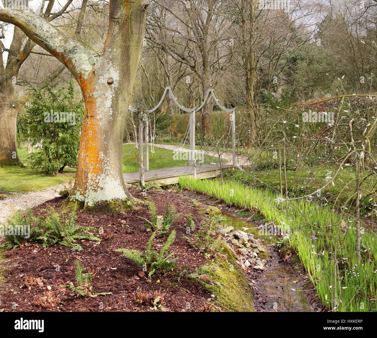 Spring in an English landscape garden with footbridge over a stream ...