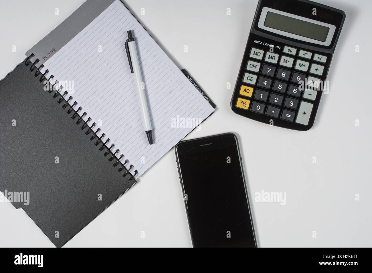 Notebook, calculator and phone with pen laying on white desk Stock ...