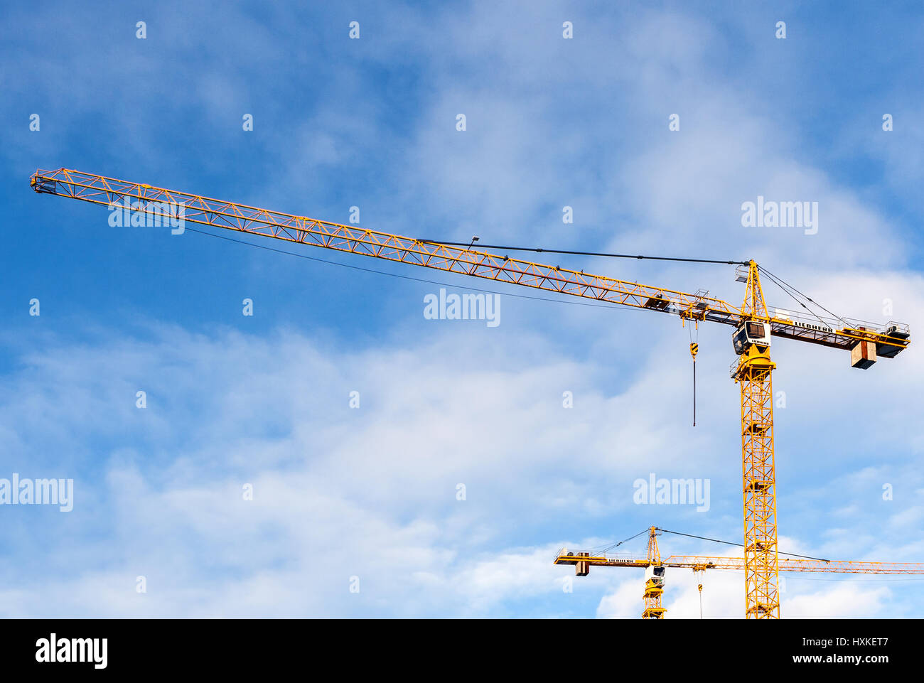 Two yellow Liebherr cranes on blue sky with clouds background Stock ...