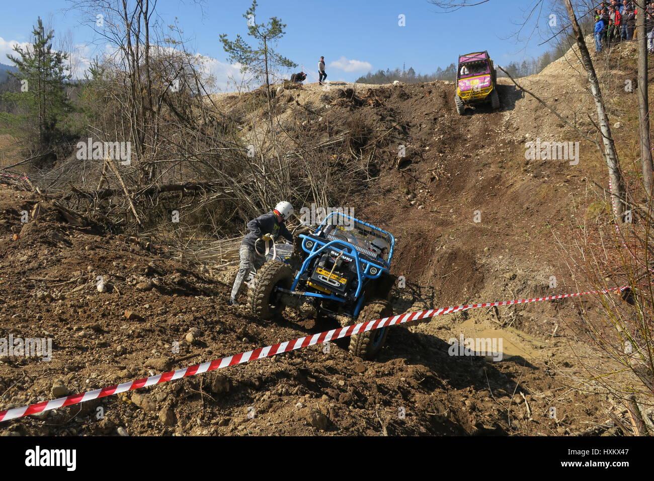 Co-driver an of off-road car is pulling a rope, steel wire to excavator ...