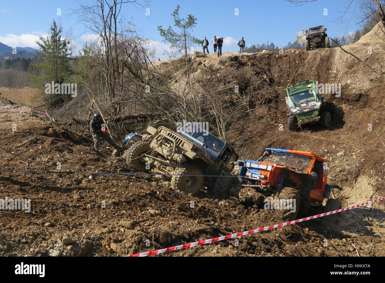 Three off-road cars are pushed uphill, co-driver pulling rope at ...