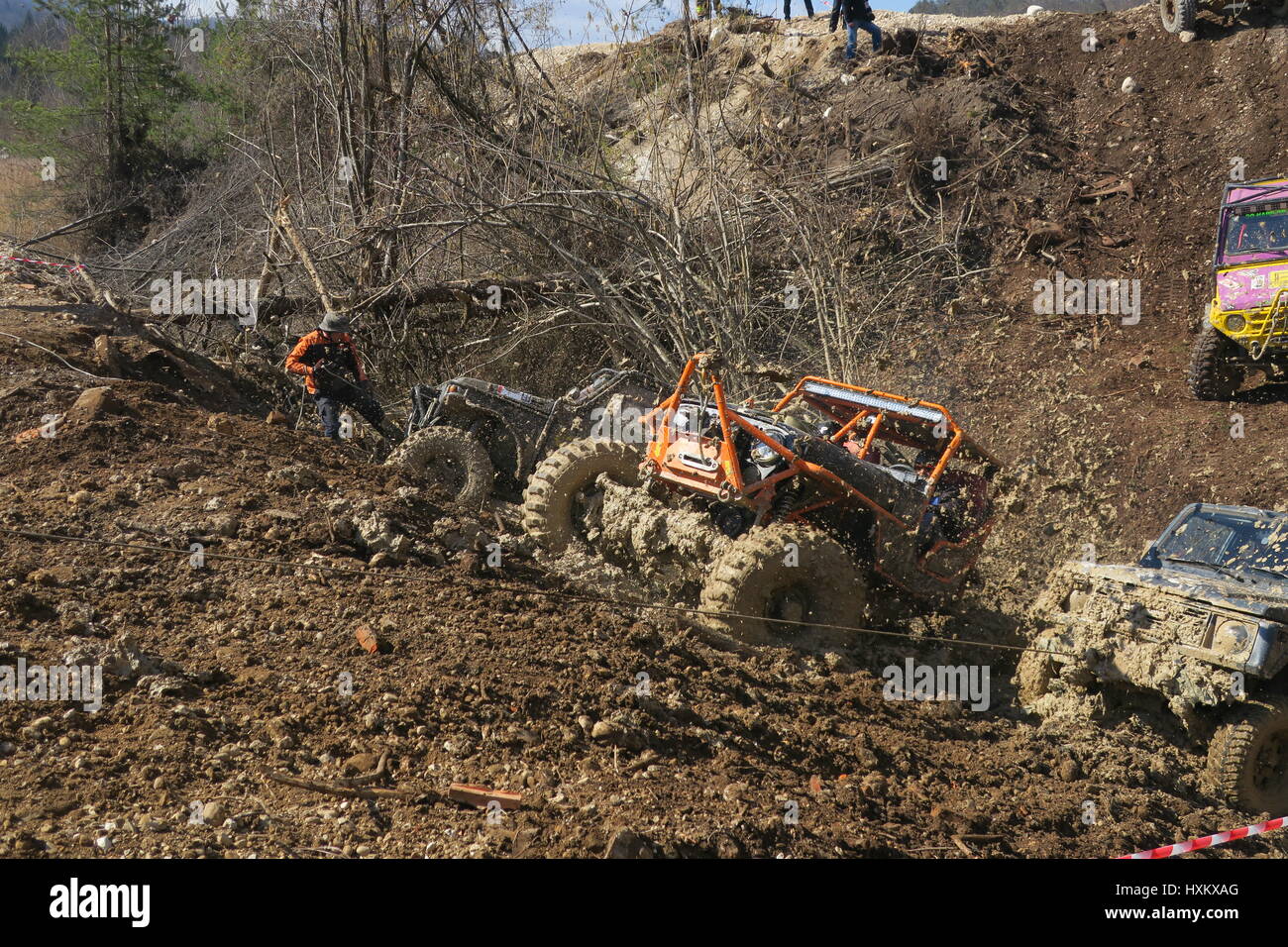 A co-driver is pulling rope of off-road car to excavator with ...