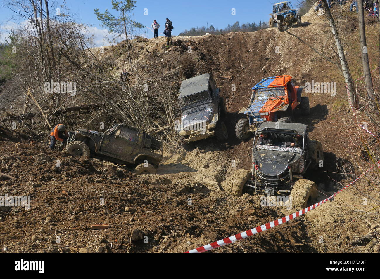 A co-driver is pulling rope of off-road car to excavator with ...