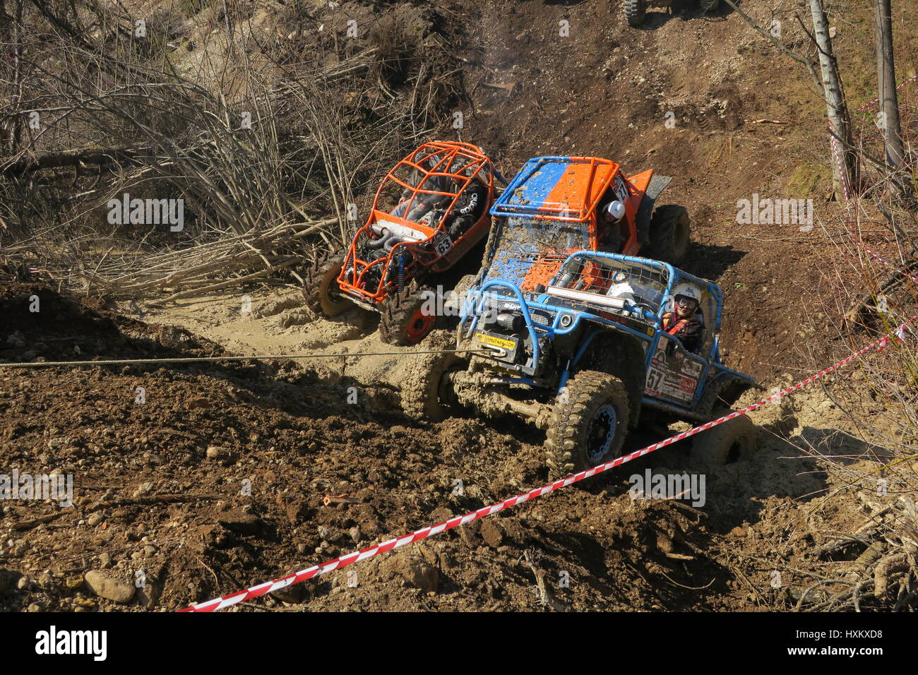 A off-road car is pulled uphill by hydraulics of an excavator, four ...