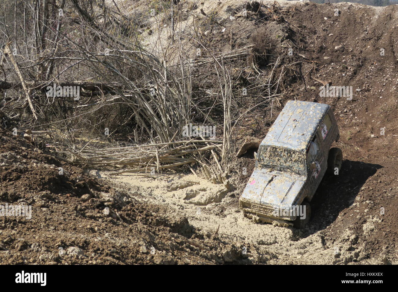 A muddy off-road car, driving downhill, got stuck in a very muddy ...